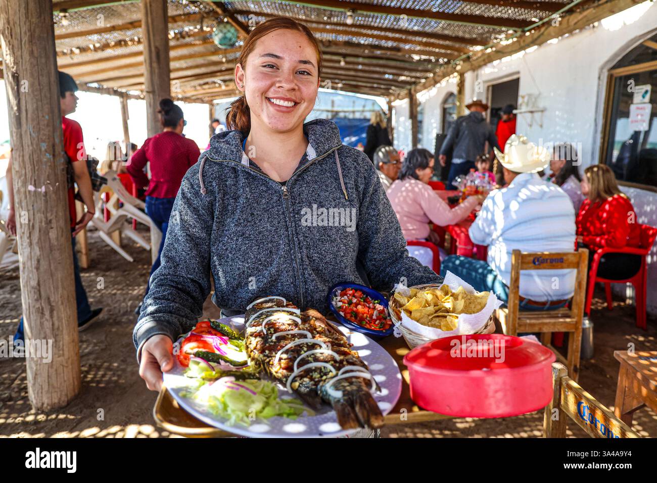 A young female waitress at El Delfin restaurant on the beach in ...