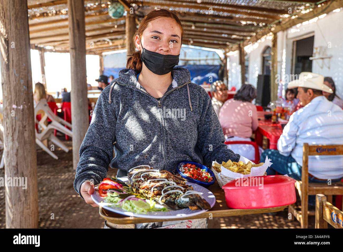A young female waitress at El Delfin restaurant on the beach in ...