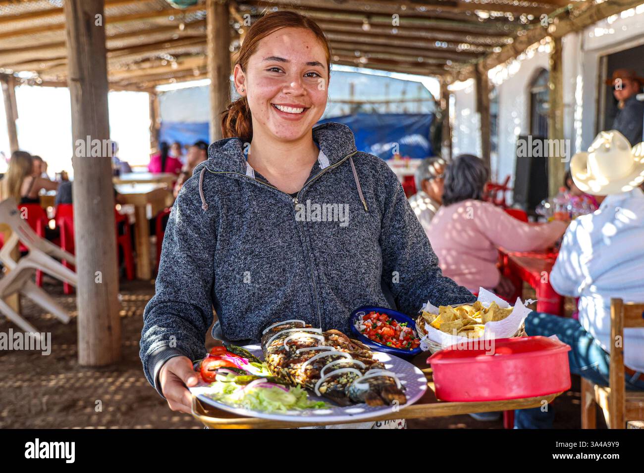 A young female waitress at El Delfin restaurant on the beach in ...