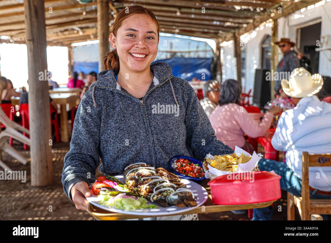 A young female waitress at El Delfin restaurant on the beach in ...