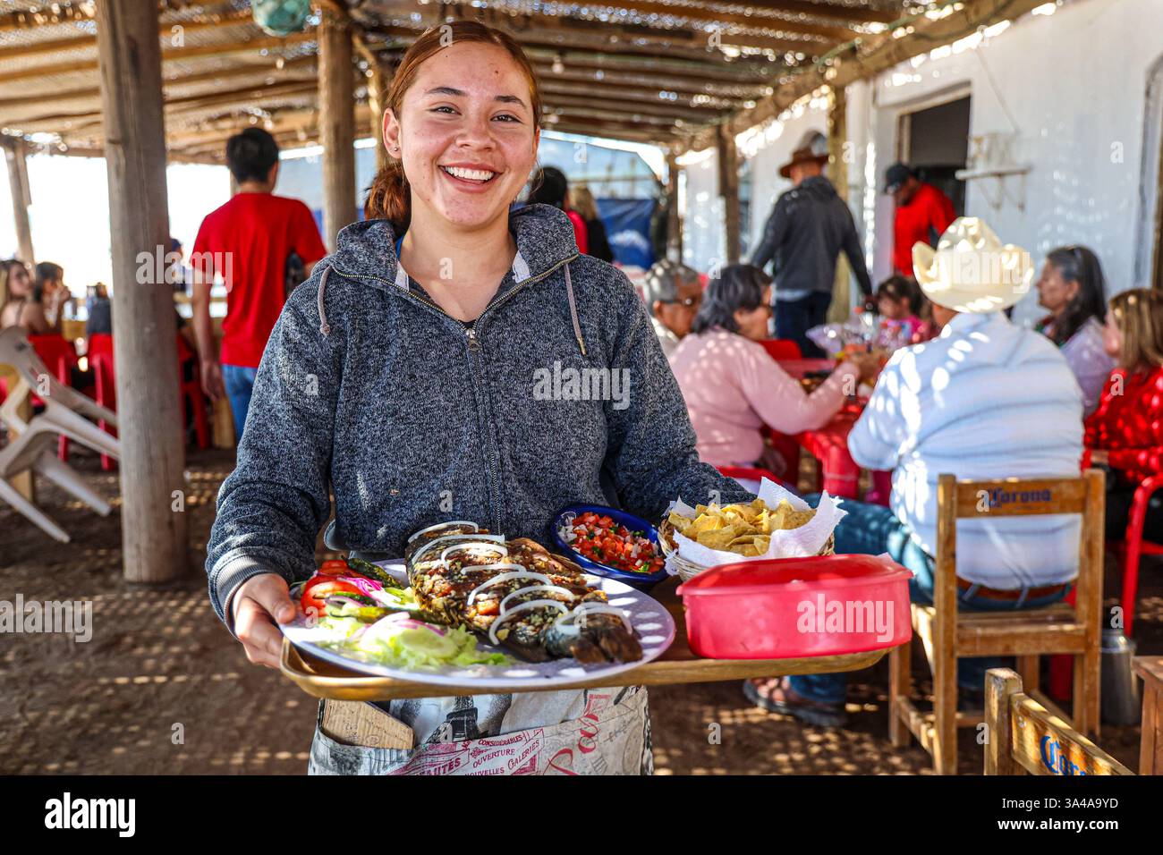 A young female waitress at El Delfin restaurant on the beach in ...