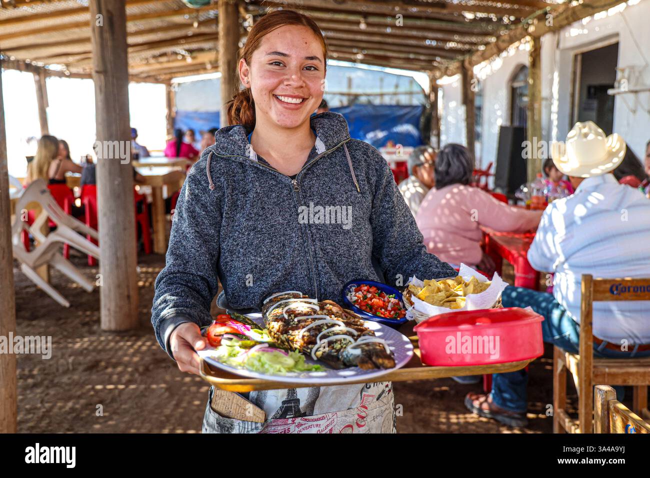 A young female waitress at El Delfin restaurant on the beach in ...