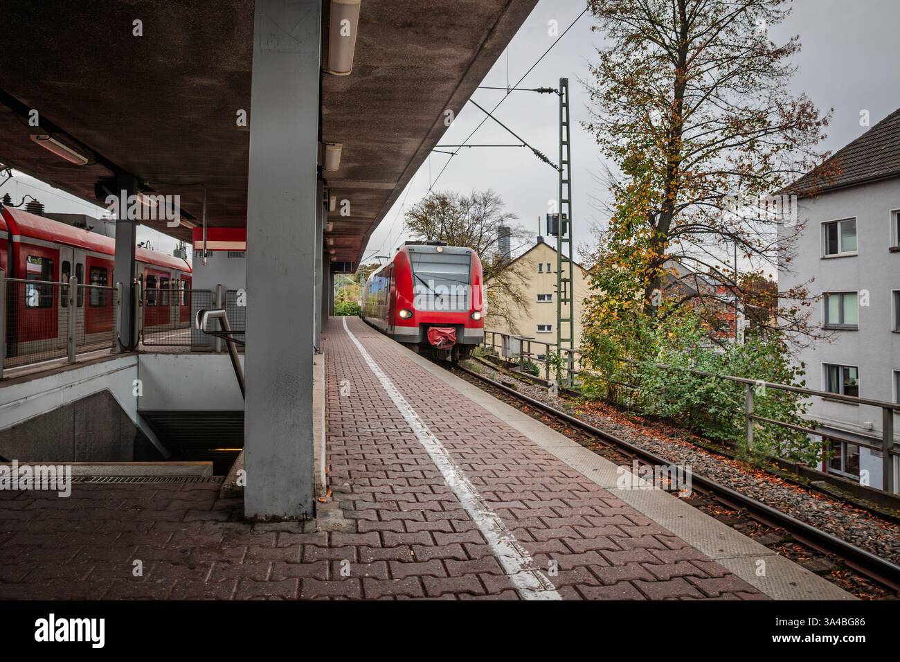 A German S-Bahn train arriving at a suburban railway station platform ...