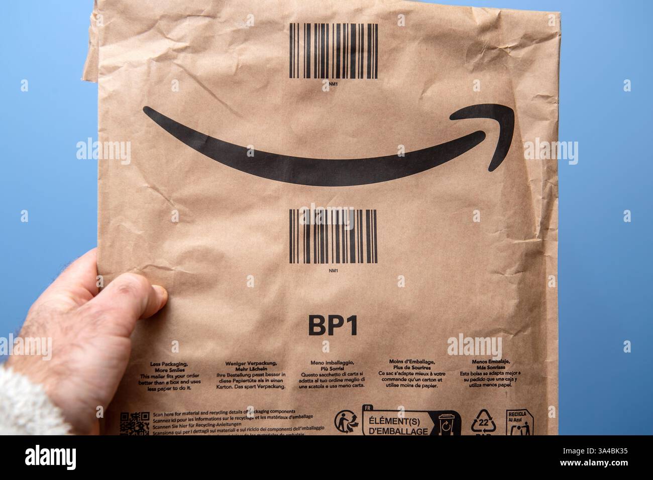 Paris, France - Mar 10, 2025: A male hand holds a crumpled brown Amazon ...