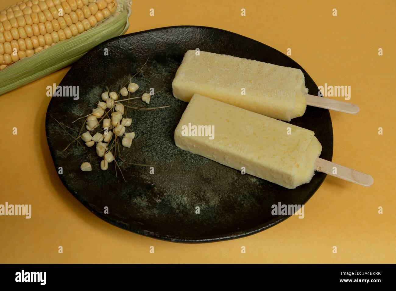 Yellow corn popsicles melting in the plate with corn kernels on a ...