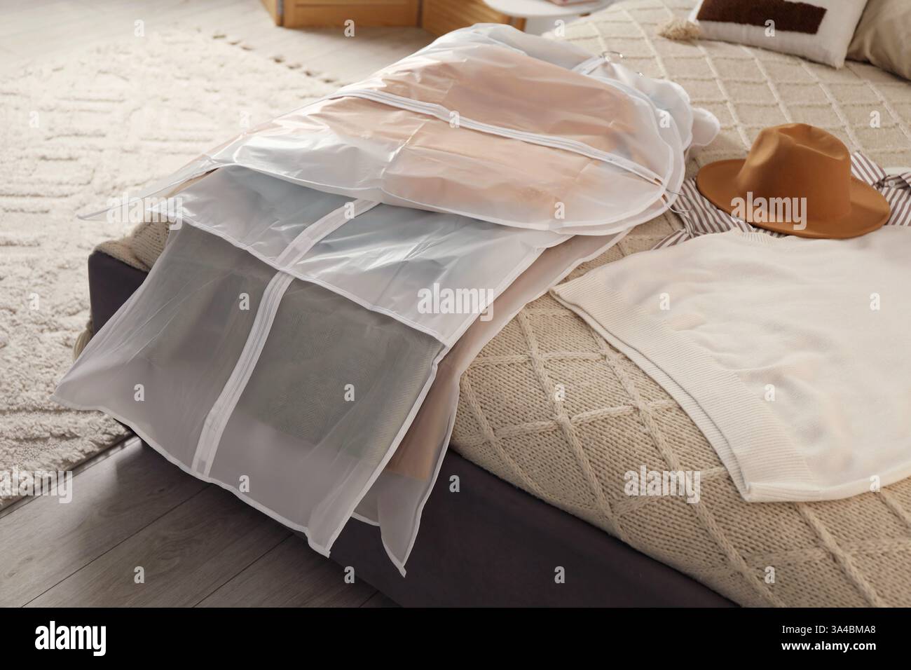Garment covers with clothes on bed indoors Stock Photo - Alamy