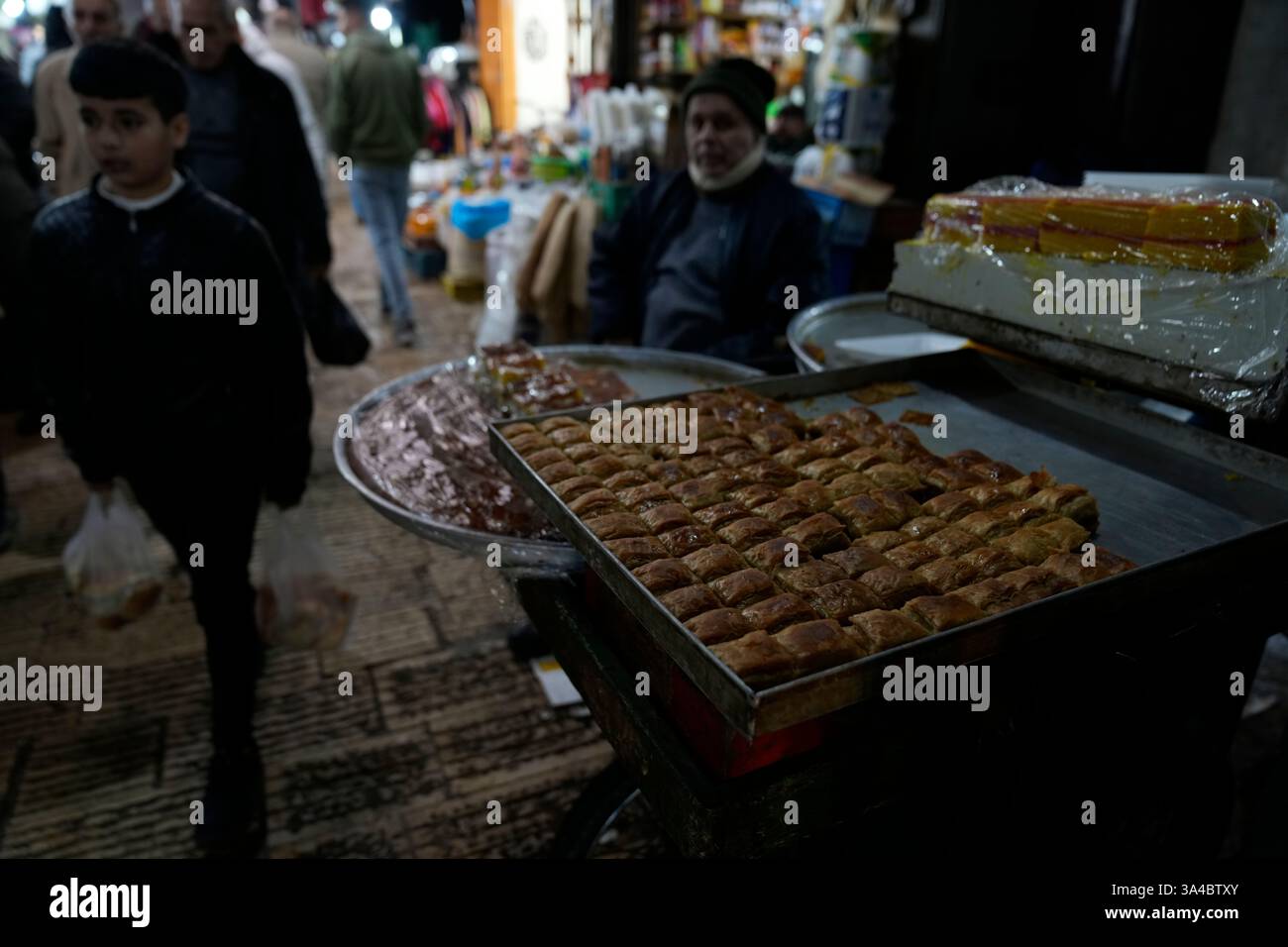 A Palestinian vendor displays Baqlawa and Hareesa traditional sweets ...