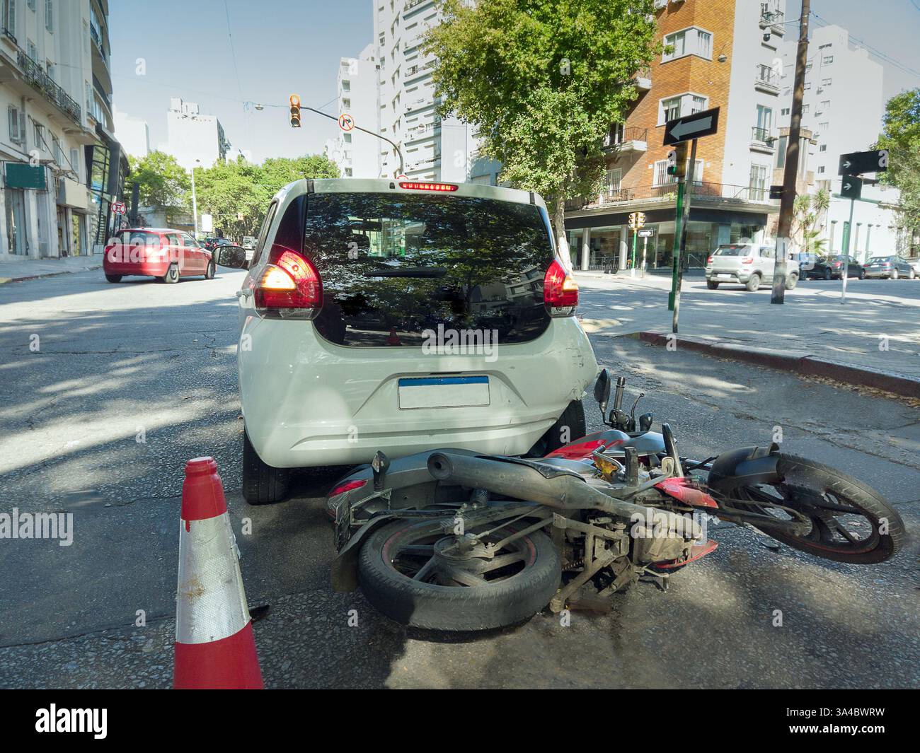 A white car and a fallen motorcycle involved in an accident at an urban ...