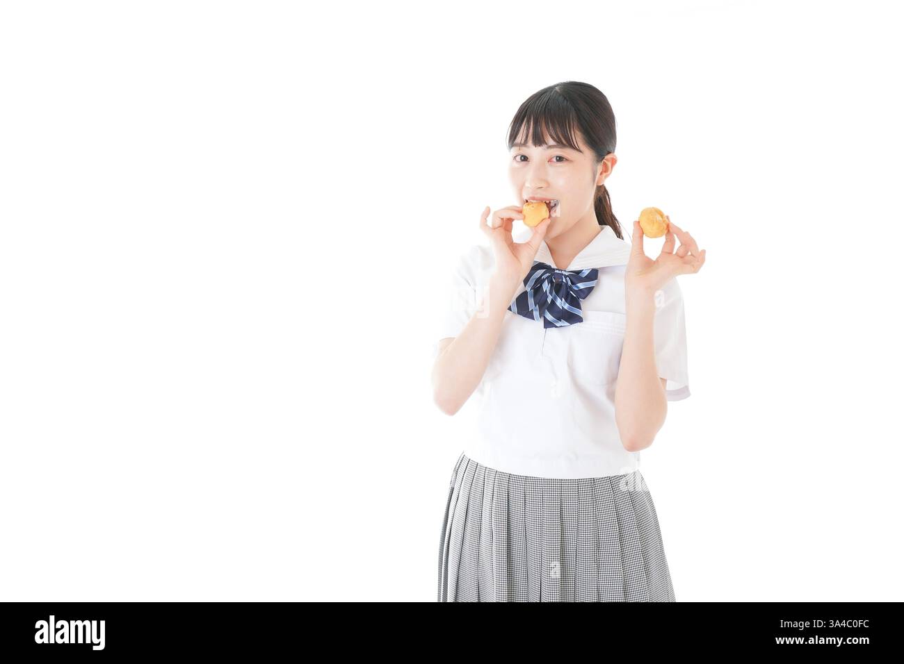 Schoolgirl in school uniform eating snack Stock Photo - Alamy