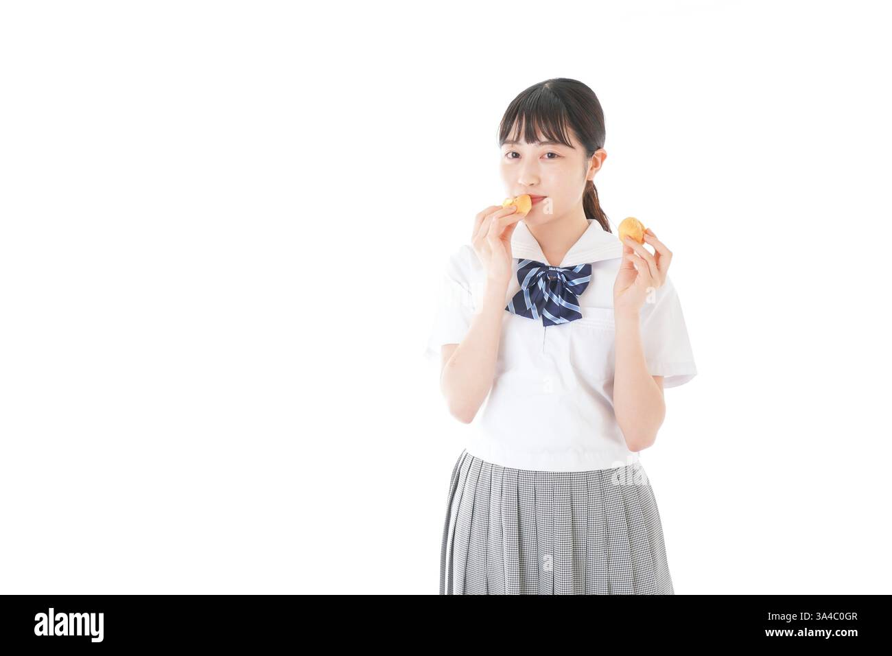 Schoolgirl in school uniform eating snack Stock Photo - Alamy