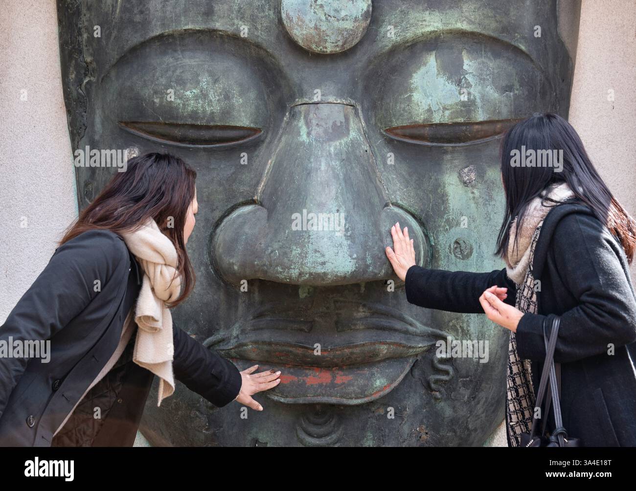 Visitors touch the "Crying" Daibutsu *Great Buddha, which is located in ...