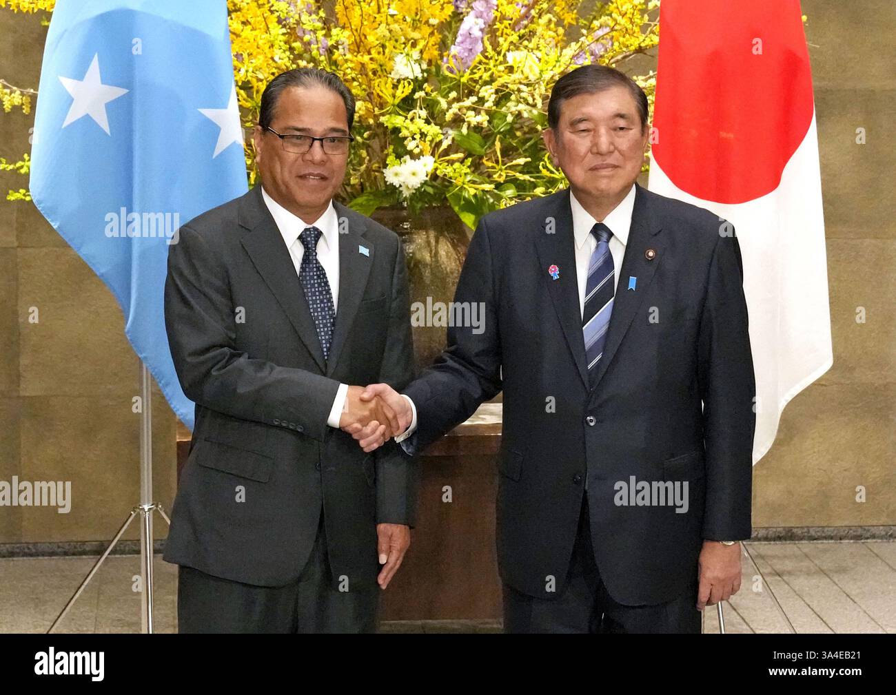 Japanese Prime Minister Shigeru Ishiba (R) shakes hands with ...
