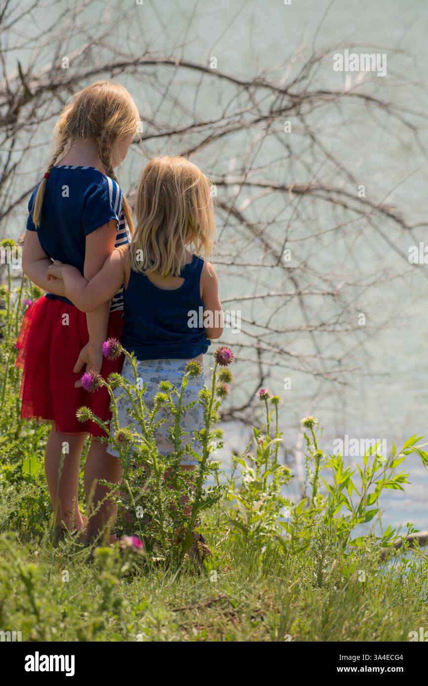 Two girls standing by pond Stock Photo - Alamy