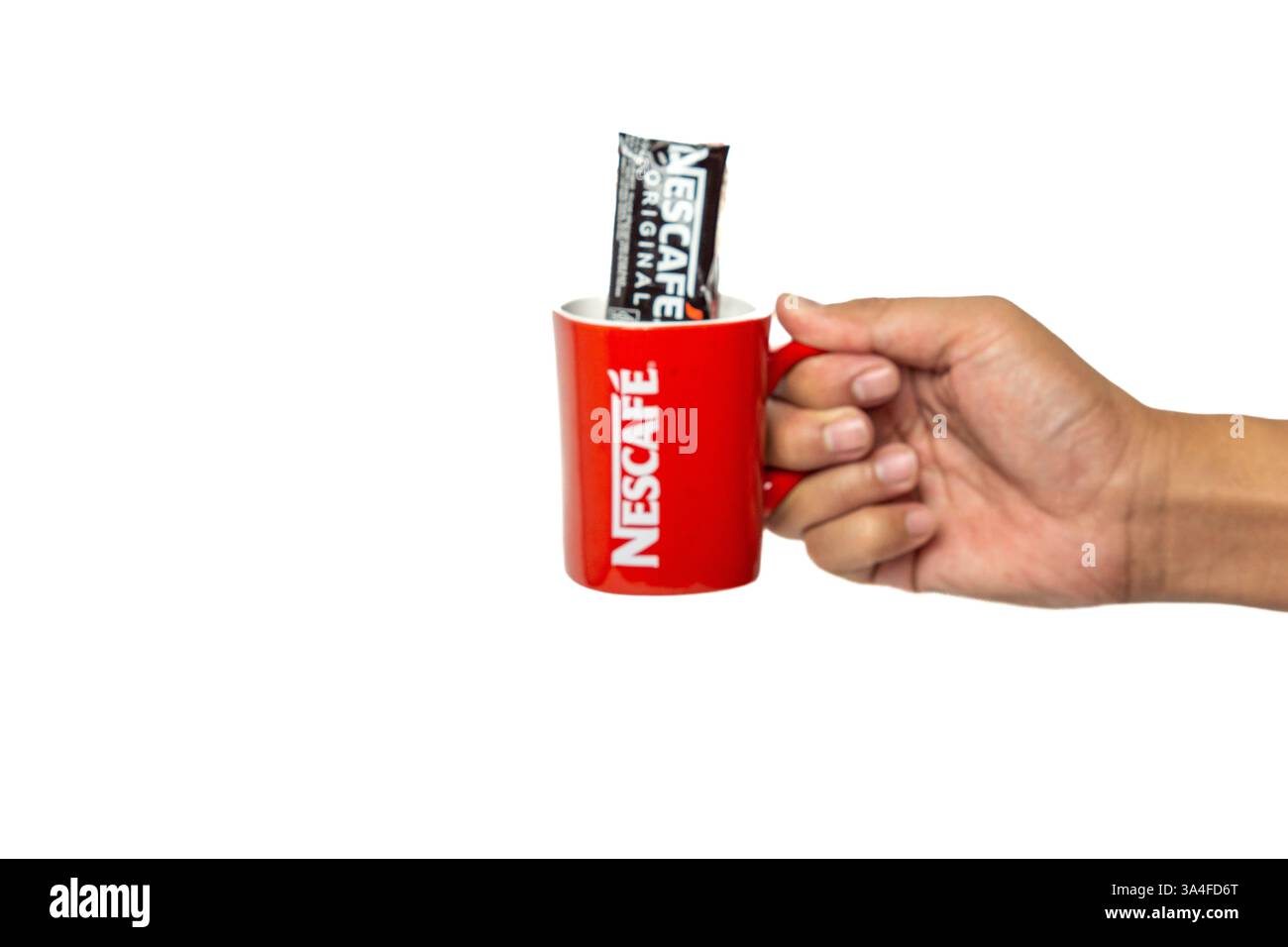 A hand is holding red mug nescafe with instant coffee in it with white ...