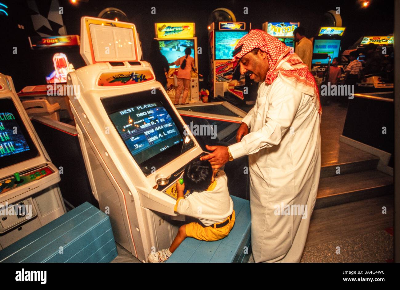 A father playing archade video games with his son in an air-conditioned ...