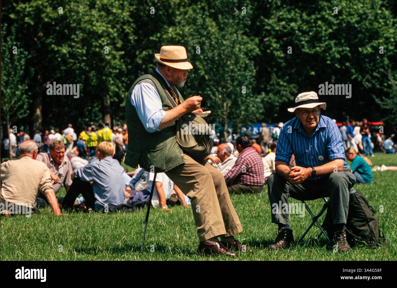 Two older men, one on a shooting stick, at a farmer's fair in rural ...