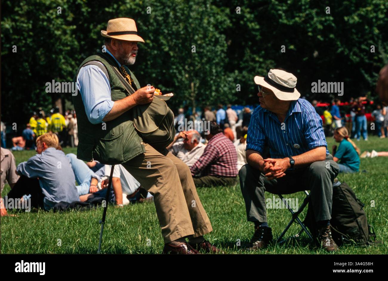Two older men, one on a shooting stick, at a farmer's fair in rural ...