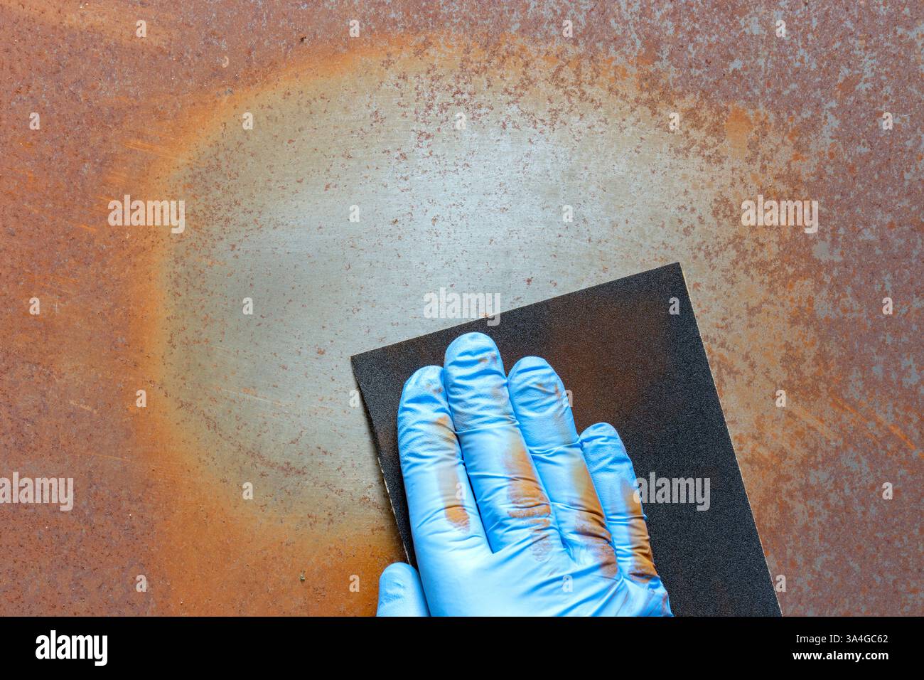 Sanding rust off sheet steel with fine grit wet and dry sandpaper ...