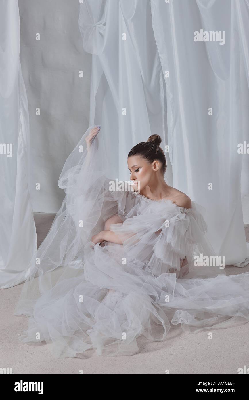 model dressed in delicate white fabric gracefully poses on a soft ...