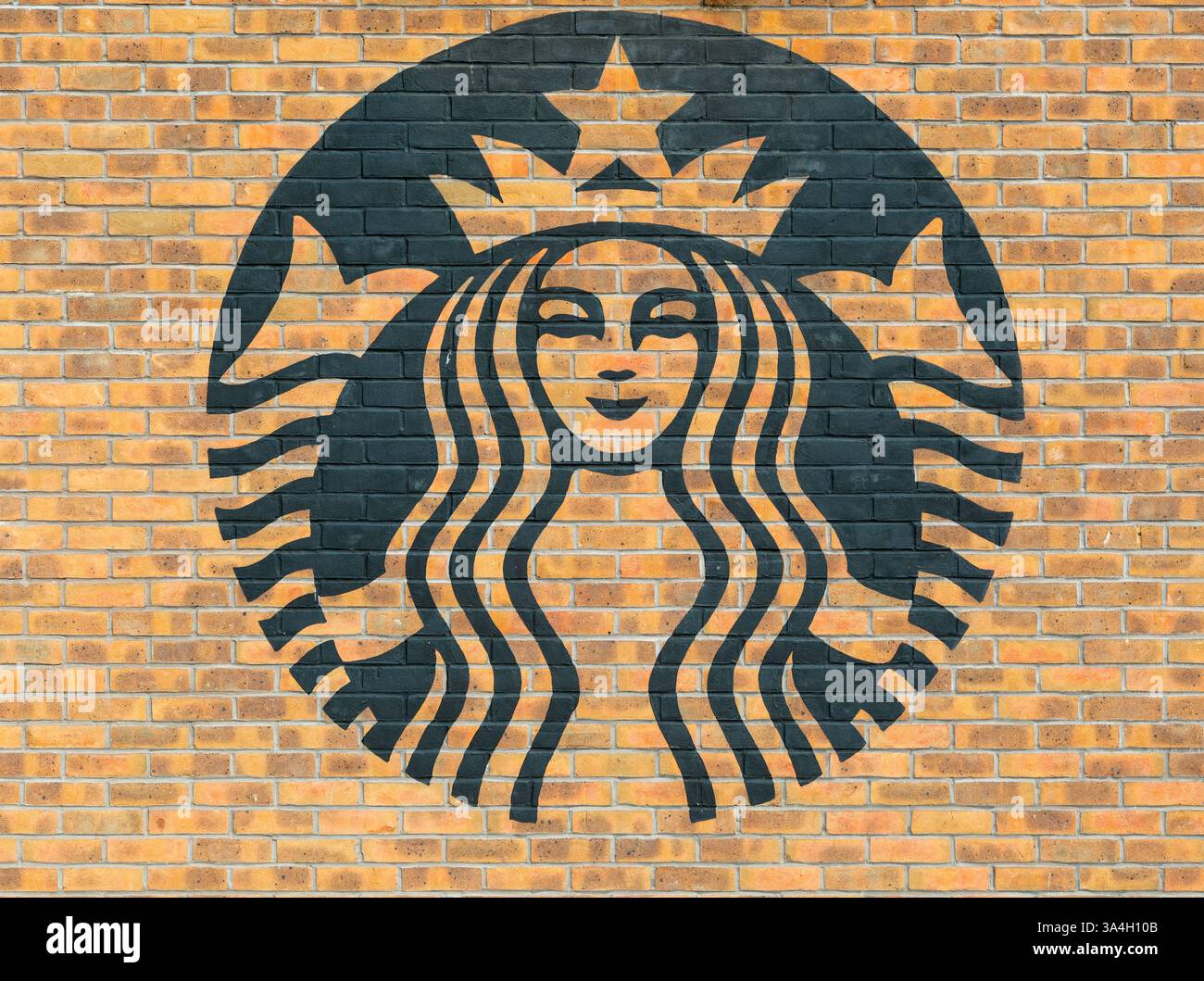 Starbucks coffee logo symbol stencilled onto wall of yellow bricks ...