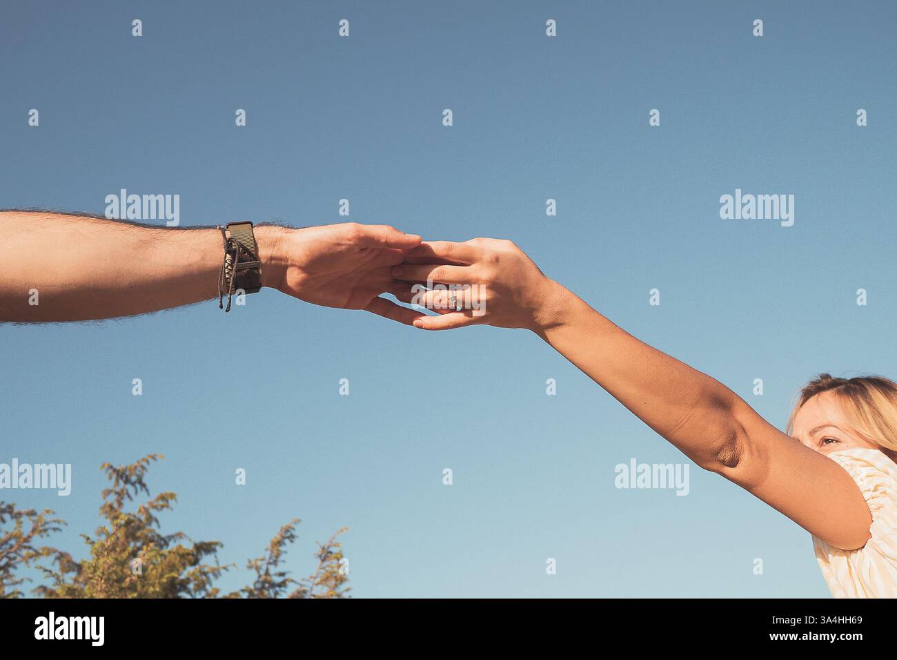 Two people extending their hands towards each other against a clear ...