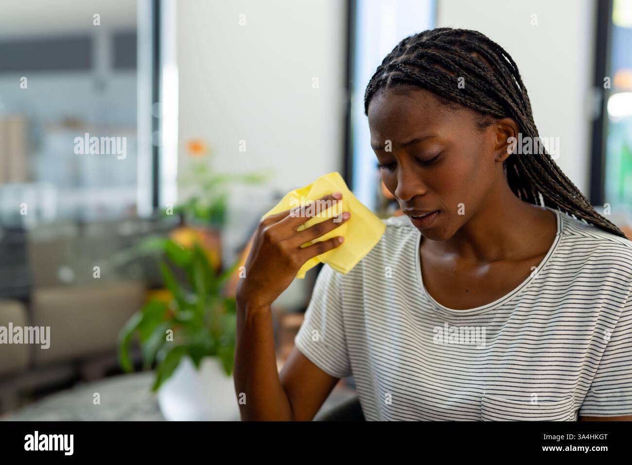 Woman wiping face with towel at home, feeling hot and tired, copy space ...