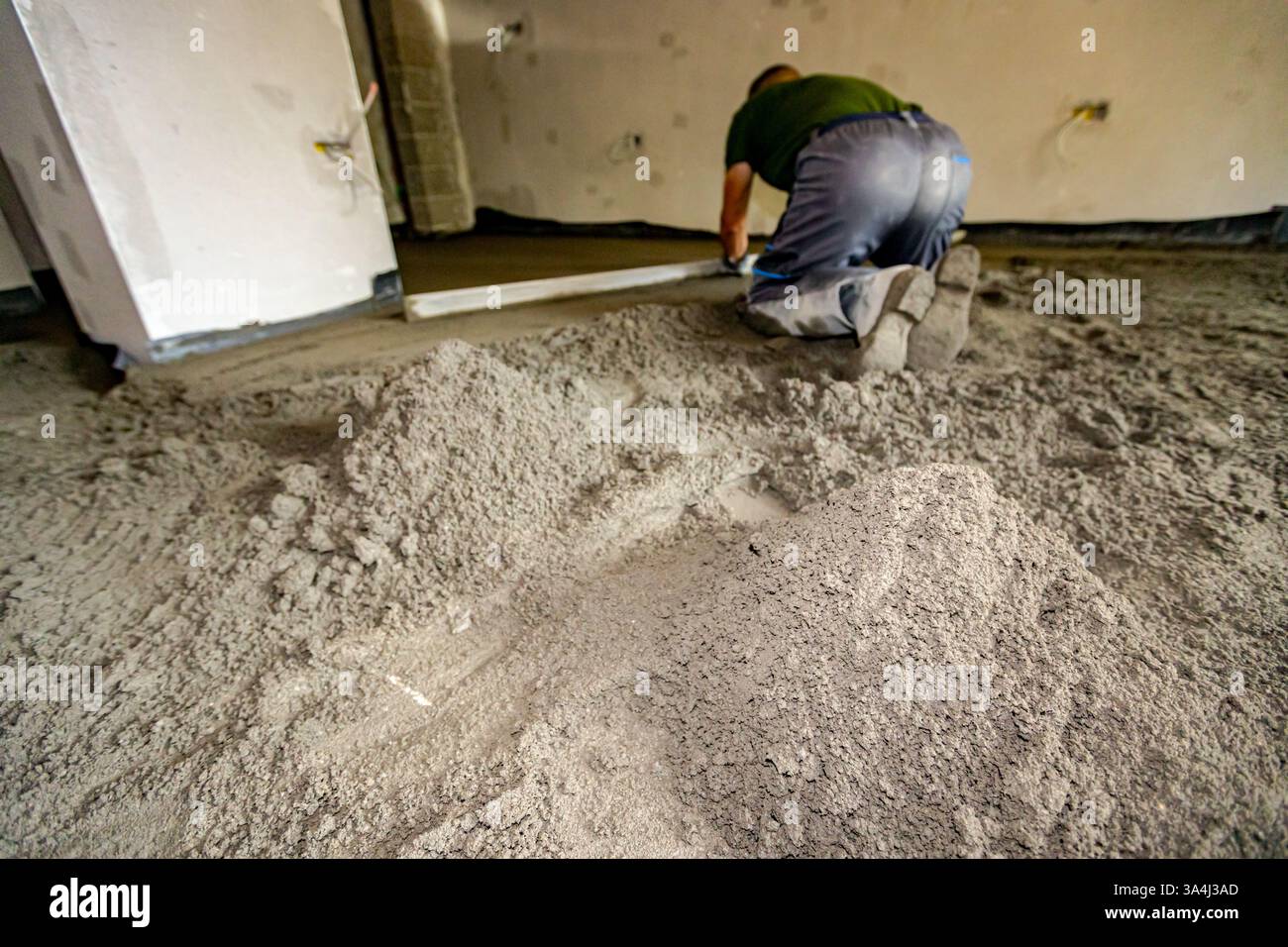 Construction worker leveling fresh semi-dry floor screed mixture of ...