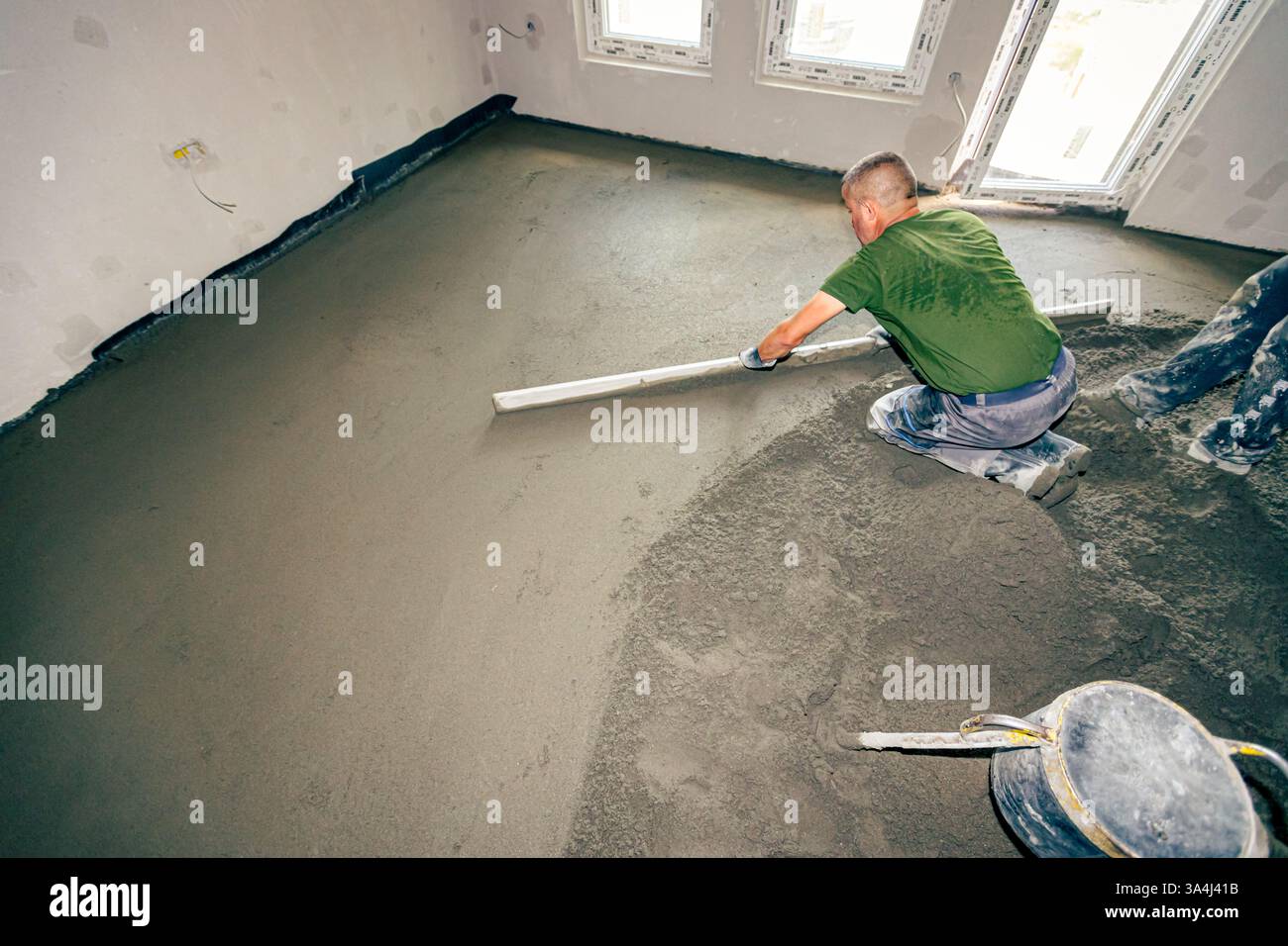 Construction worker leveling fresh semi-dry floor screed mixture of ...