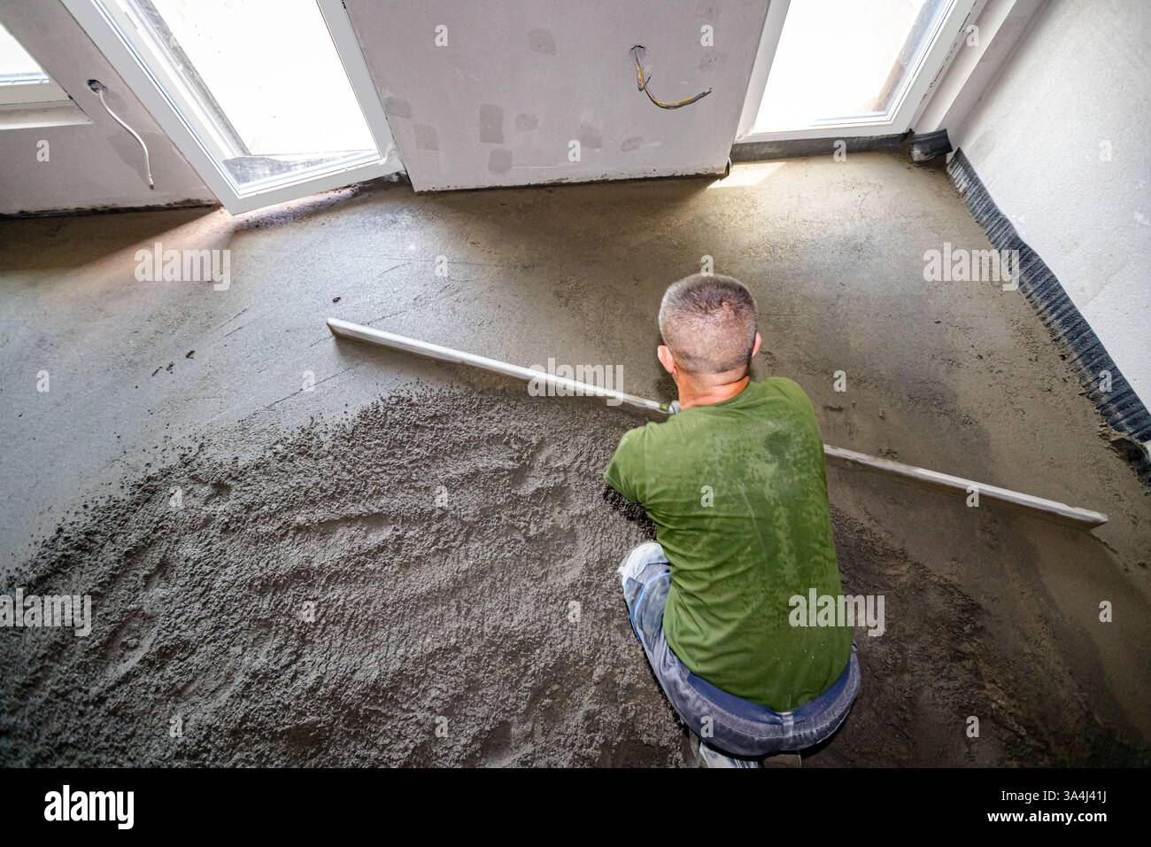 Construction worker leveling fresh semi-dry floor screed mixture of ...