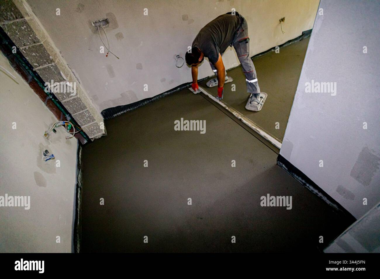 Construction worker leveling fresh semi-dry floor screed mixture of ...