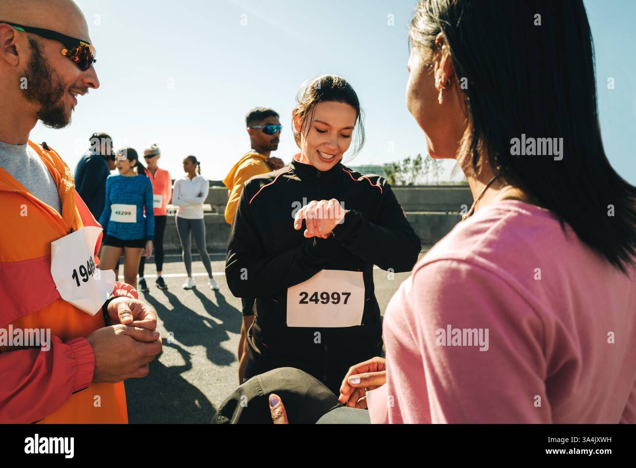 A diverse group of runners gather at the starting line of a marathon ...