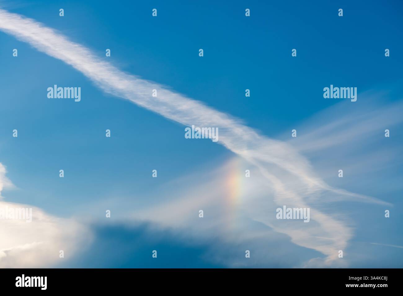 Sky with cirrus, stratus clouds, airplane trail and halo from the sun ...