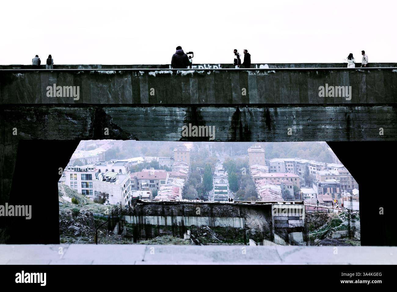 A weathered concrete bridge frames a view of Yerevan with residential ...