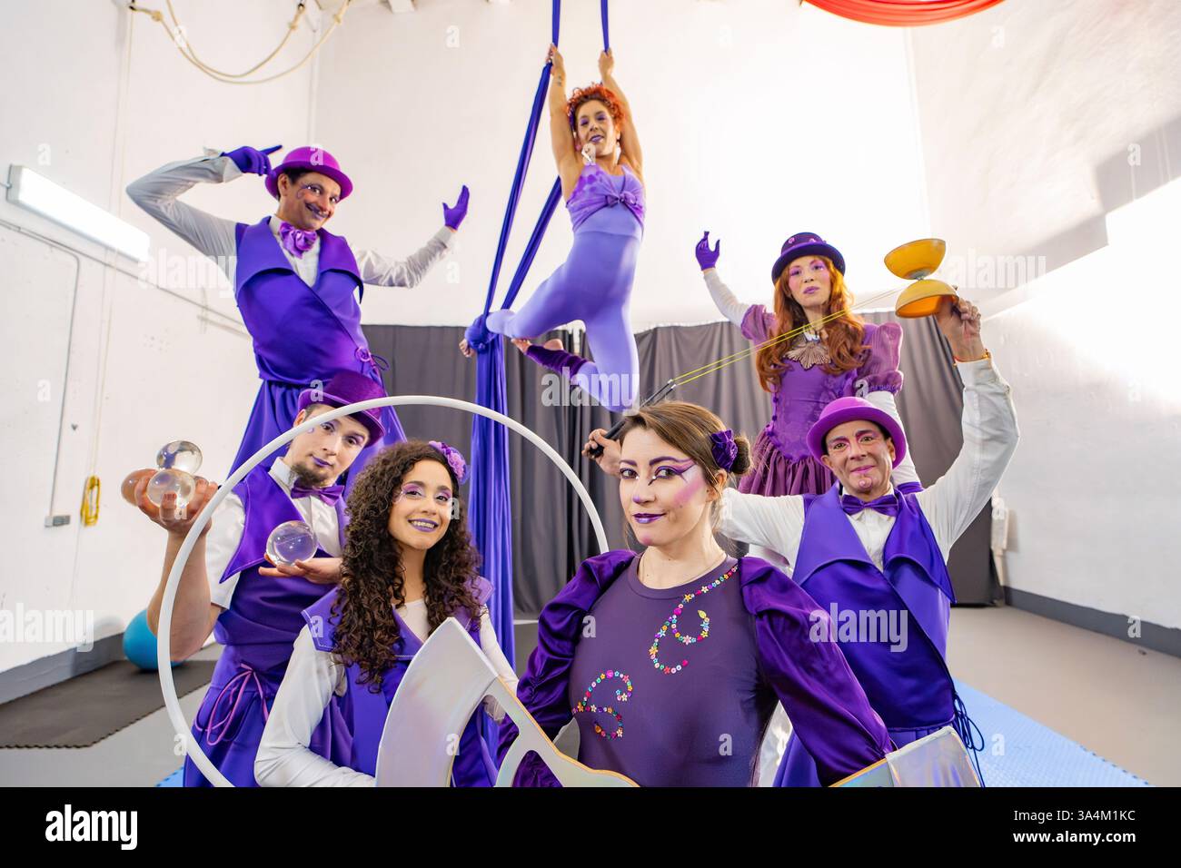 Group of circus performers wearing purple costumes showing their skills ...