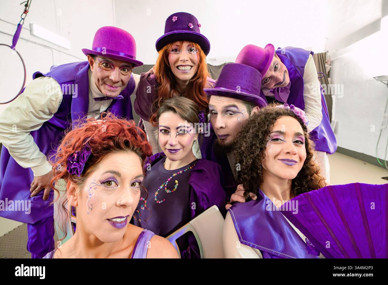 Group of smiling circus performers wearing purple costumes and makeup ...