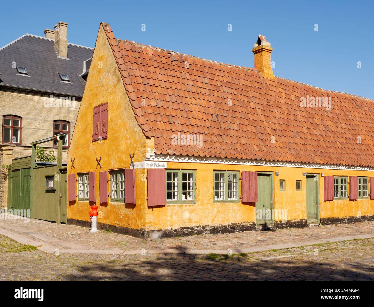 Colorful historic corner house with red roof tiles and yellow walls ...