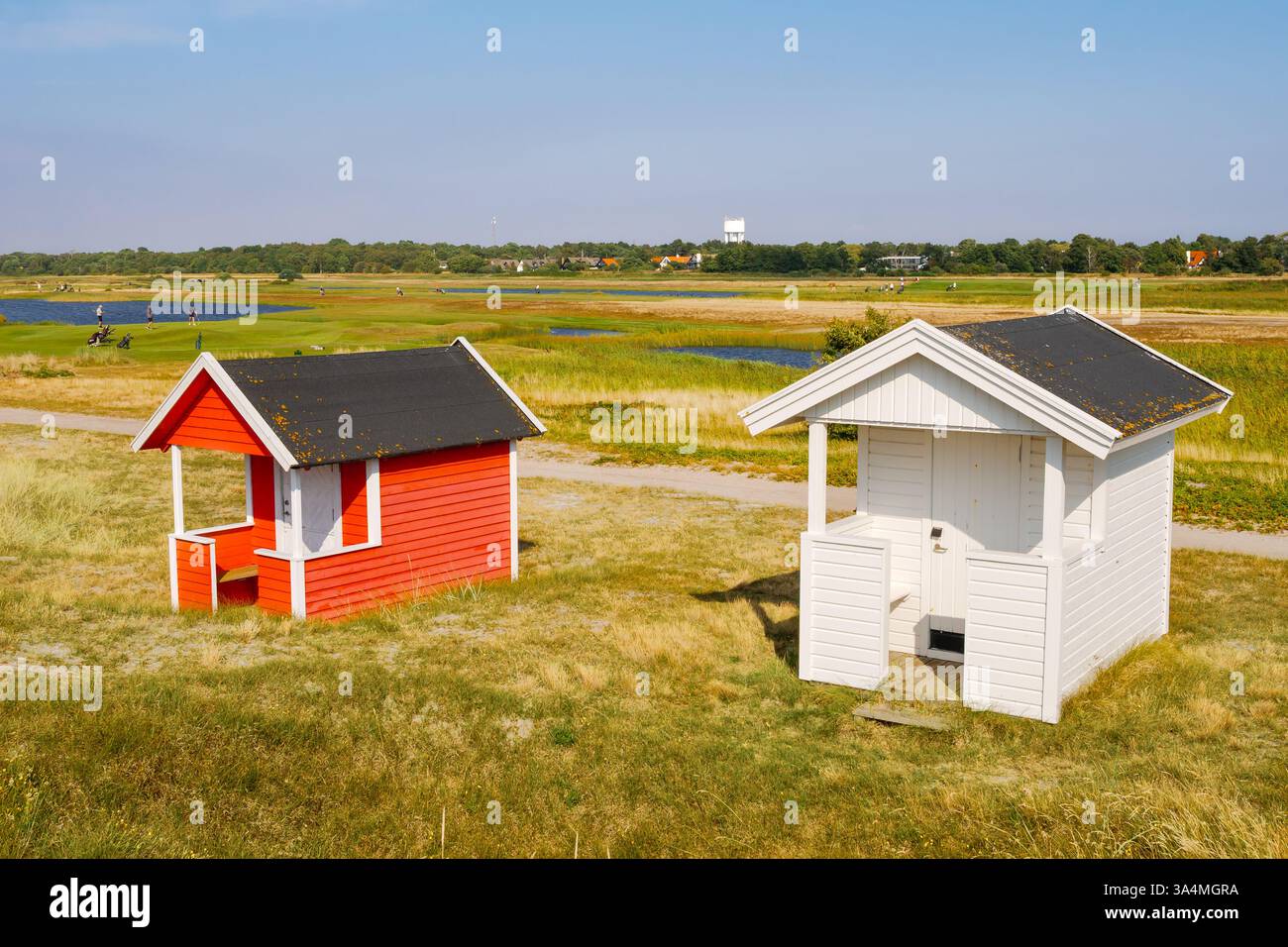 Two small beach or bathing huts in red and white nestled among dunes ...