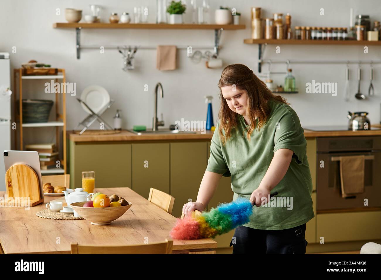 Young woman with Down syndrome enjoys cleaning her inviting kitchen ...