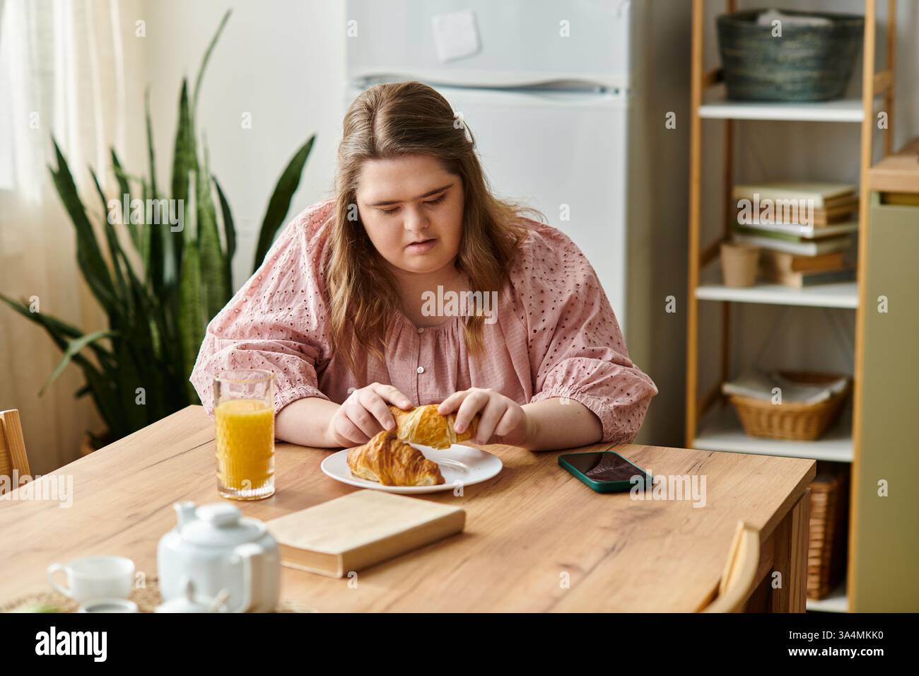 A young woman with Down syndrome enjoys a cozy breakfast at home ...