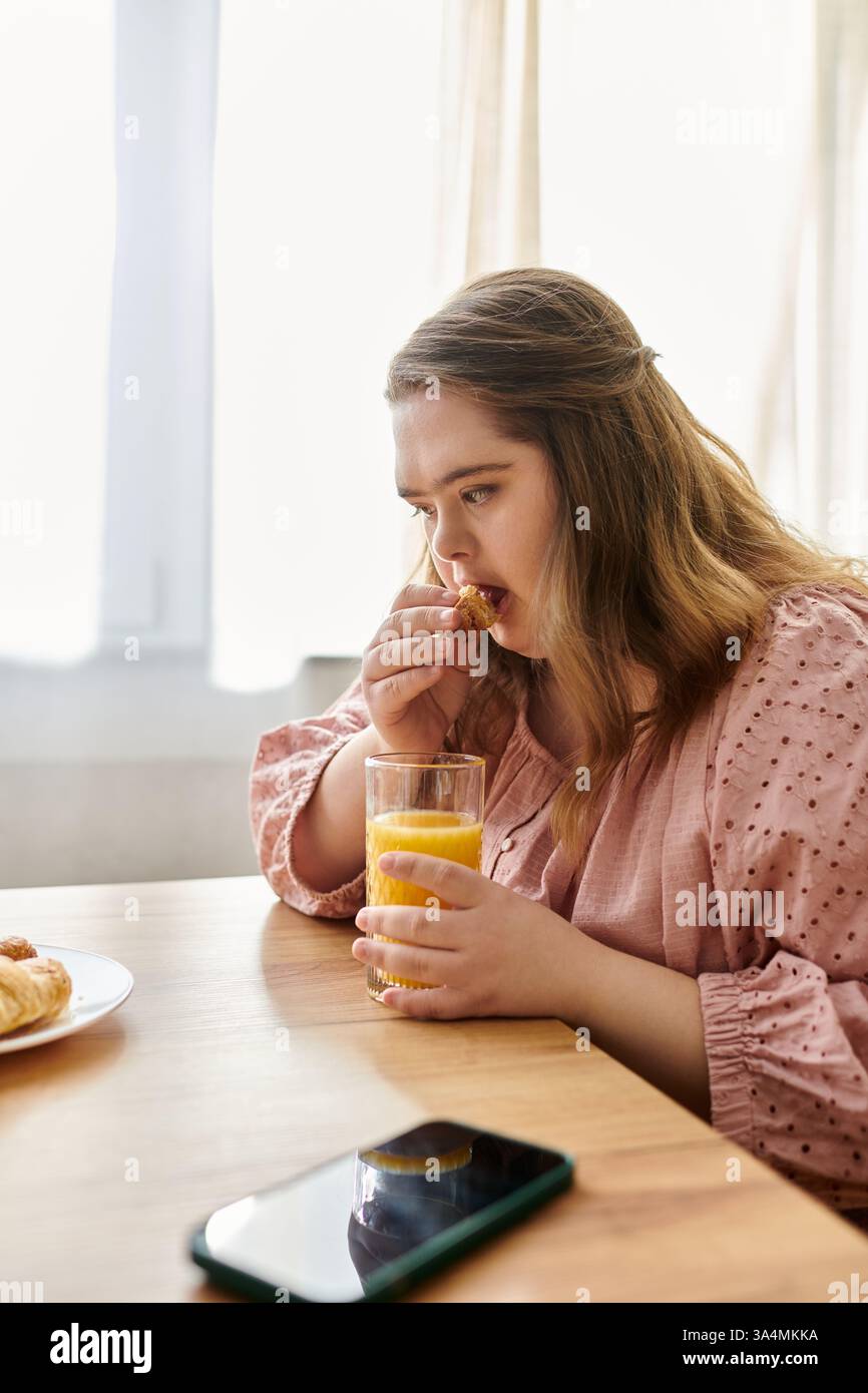 A young pretty woman with Down syndrome enjoys a peaceful breakfast at ...