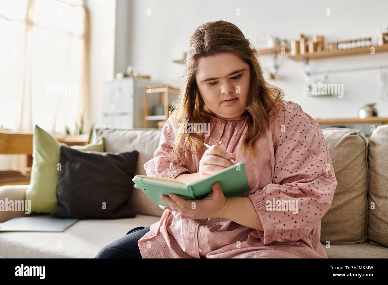 Pretty young woman enjoys writing in a comfortable nook of her home ...