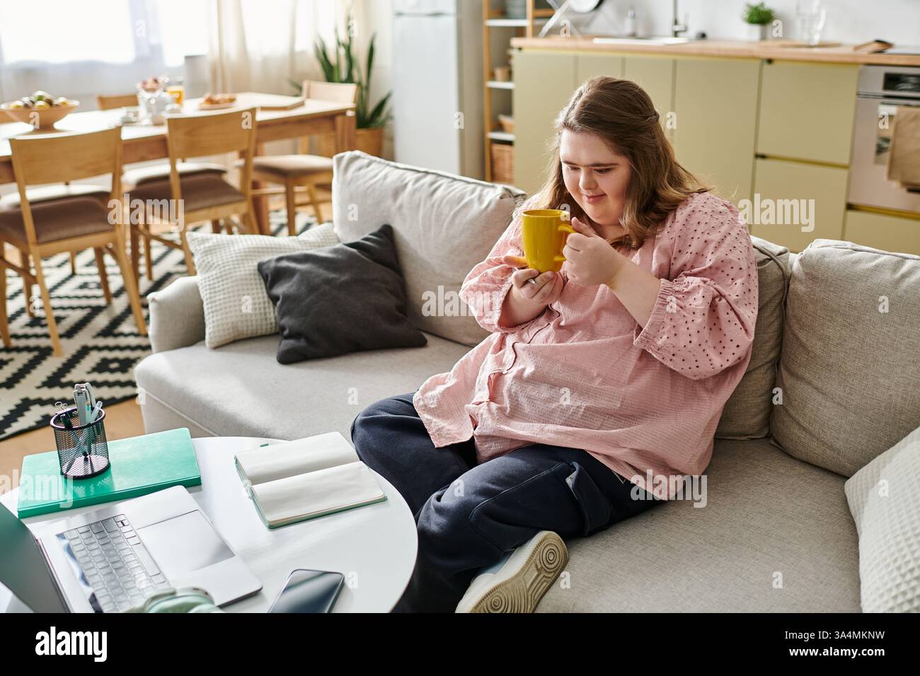 A young woman with Down syndrome sips tea, cherishing cozy moments at ...