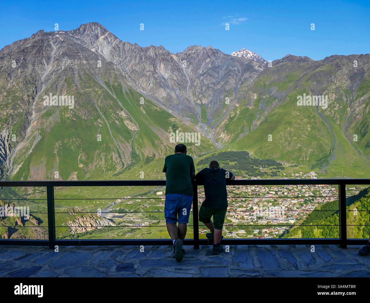 Father and son hikers look out over the village of Stepantsminda in the ...