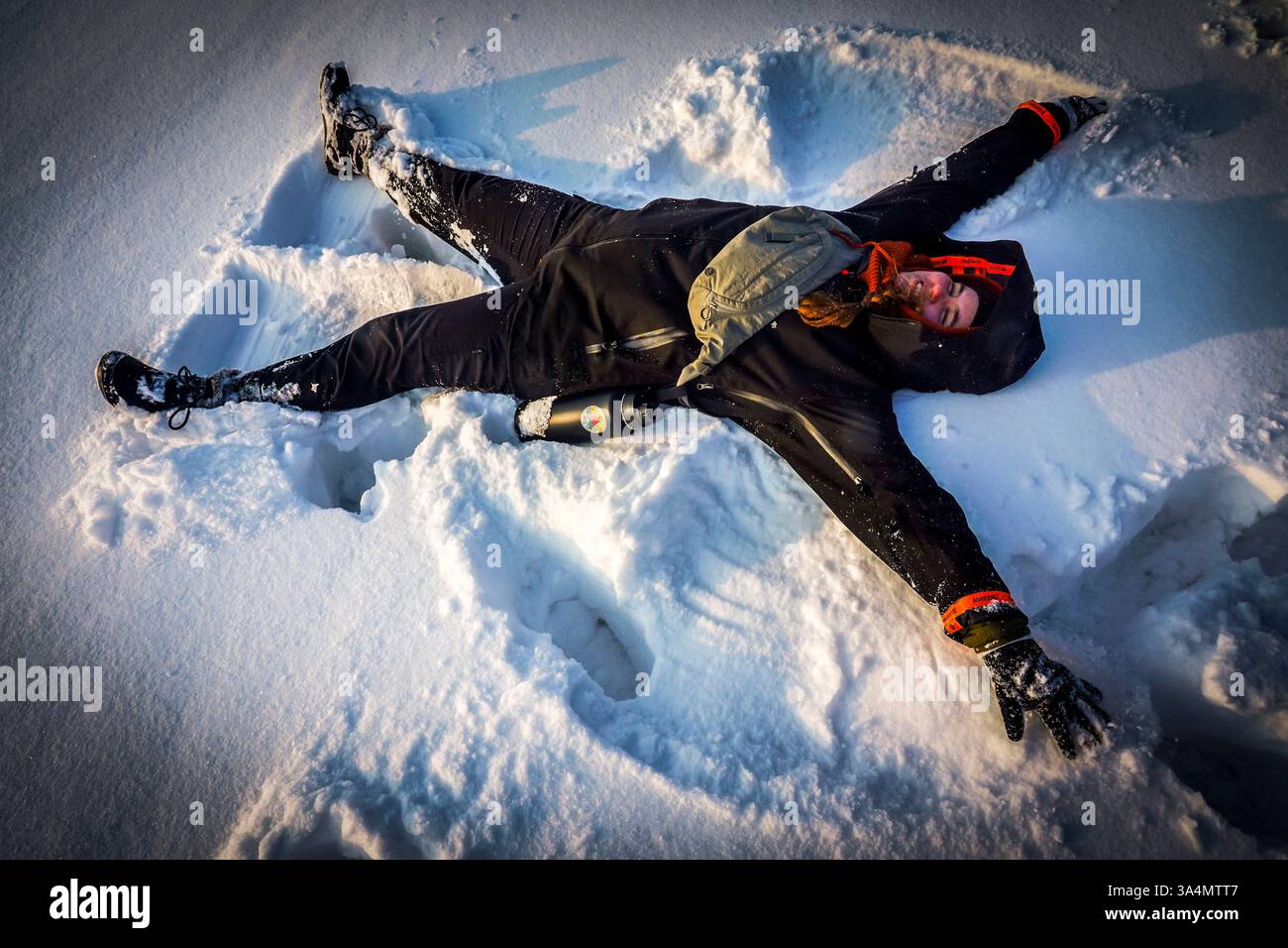 A girl making snow angels on a mountain hike Stock Photo - Alamy