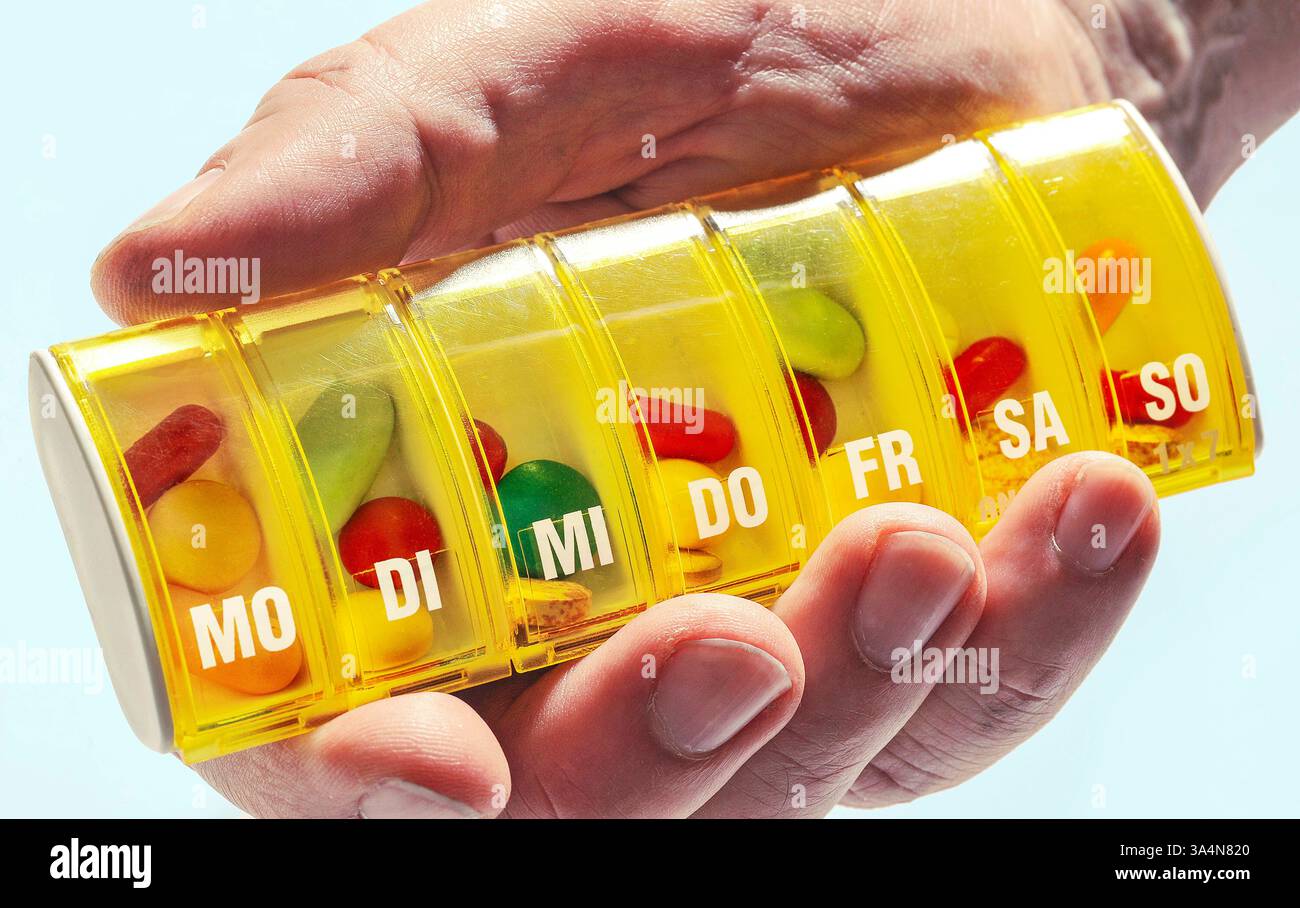 Medikamente einnehmen, Hand hält Pillenbox mit Wochenration an ...