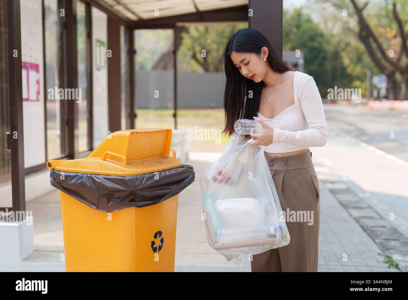 Sustainability and Recycling Awareness. A woman responsibly disposing of recyclables in a ...
