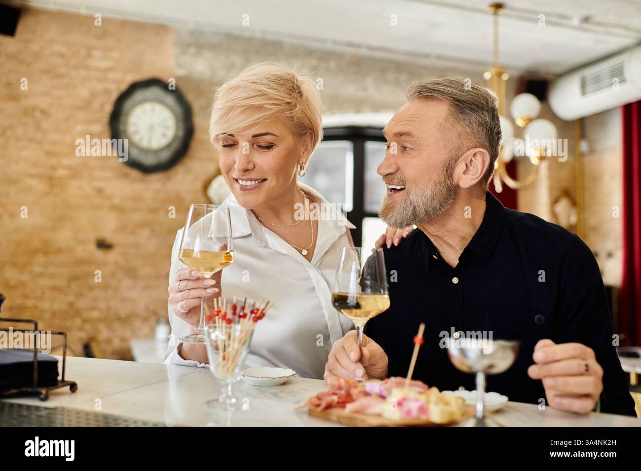 A middle-aged couple shares laughter and wine while indulging in ...