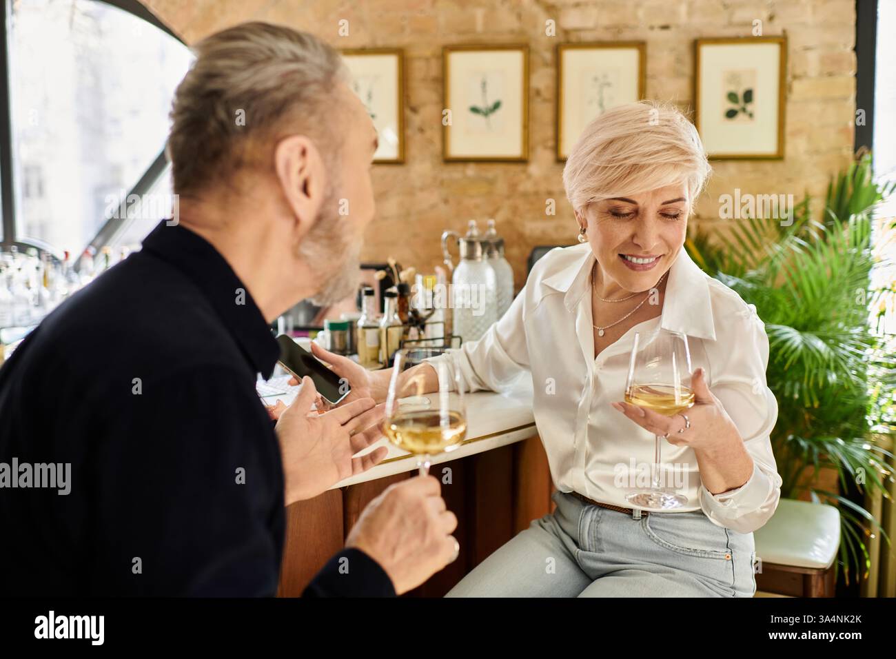 A beautiful mature couple shares laughter and drinks at a charming bar ...
