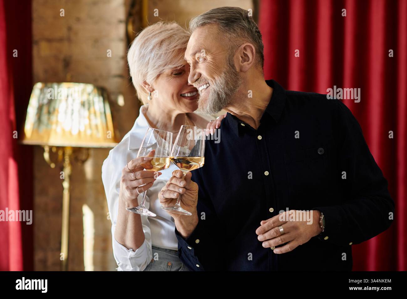A middle aged man and woman share a joyful moment, clinking glasses in ...