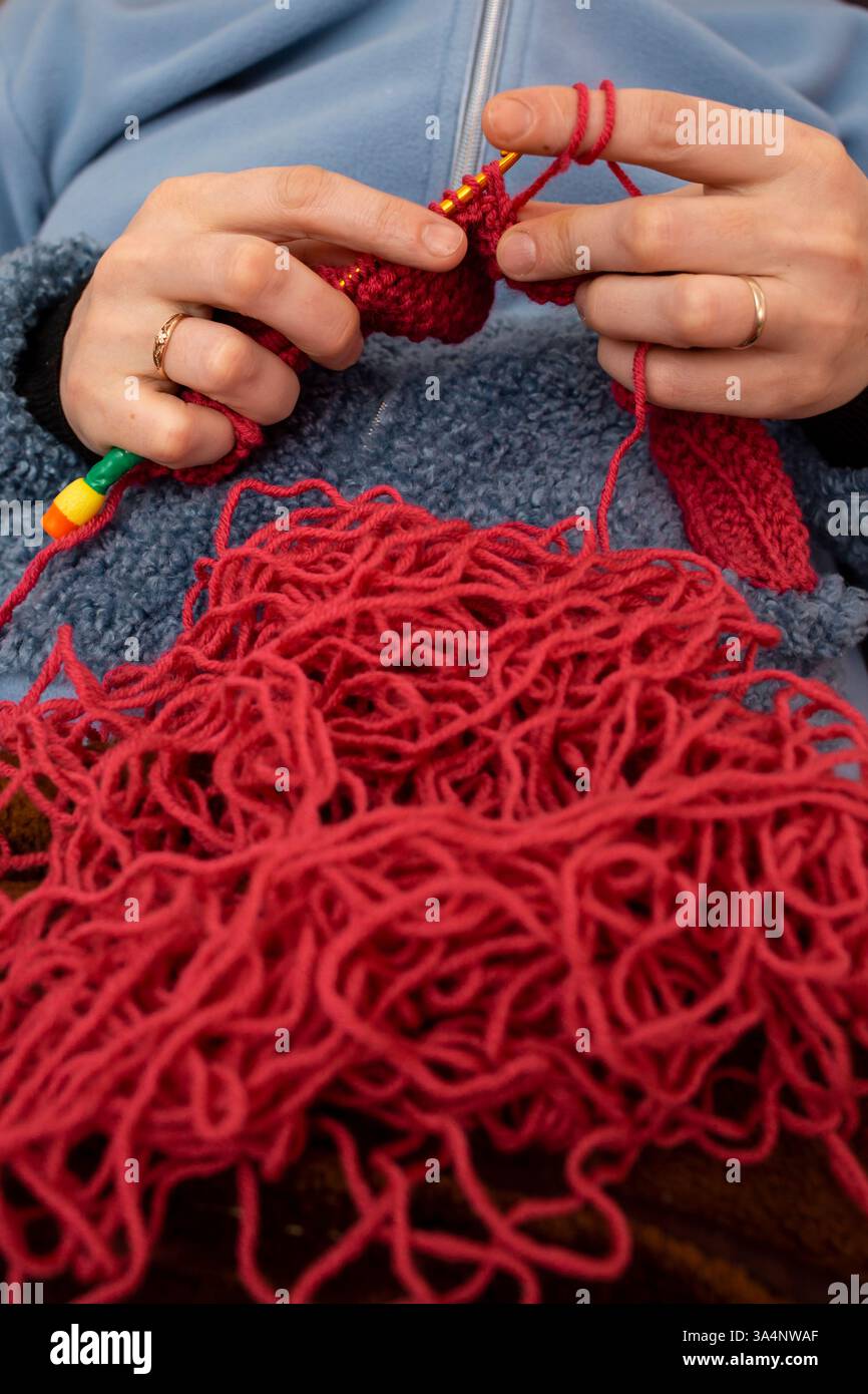 Red tangled thread with defocused Womans hands knitting with a crochet ...